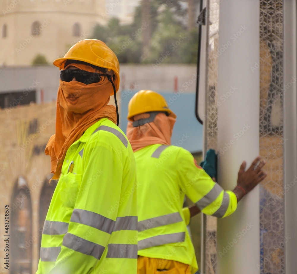 Two blue-collar workers wearing helmets and yellow jackets working ...