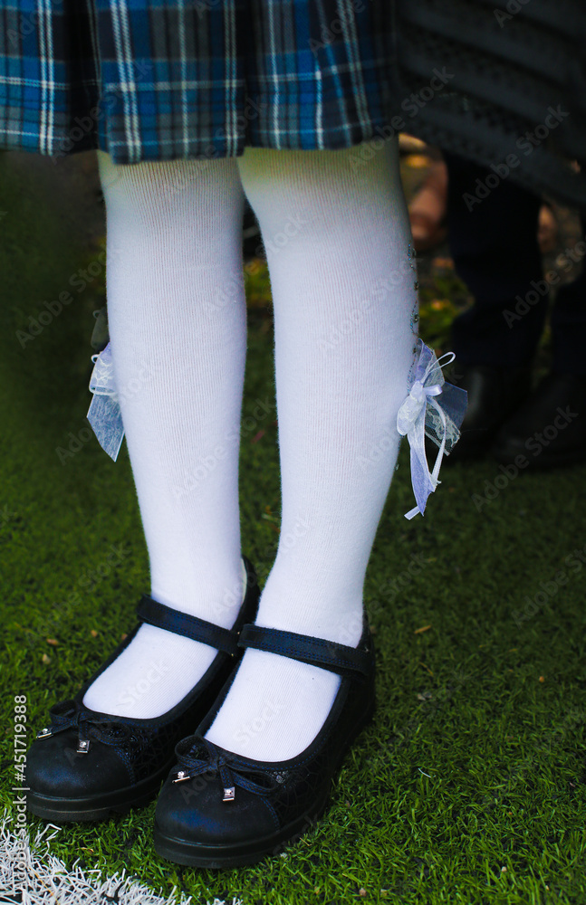 Legs in cute shoes and white socks of 1-st graders (pupils) in uniform ...