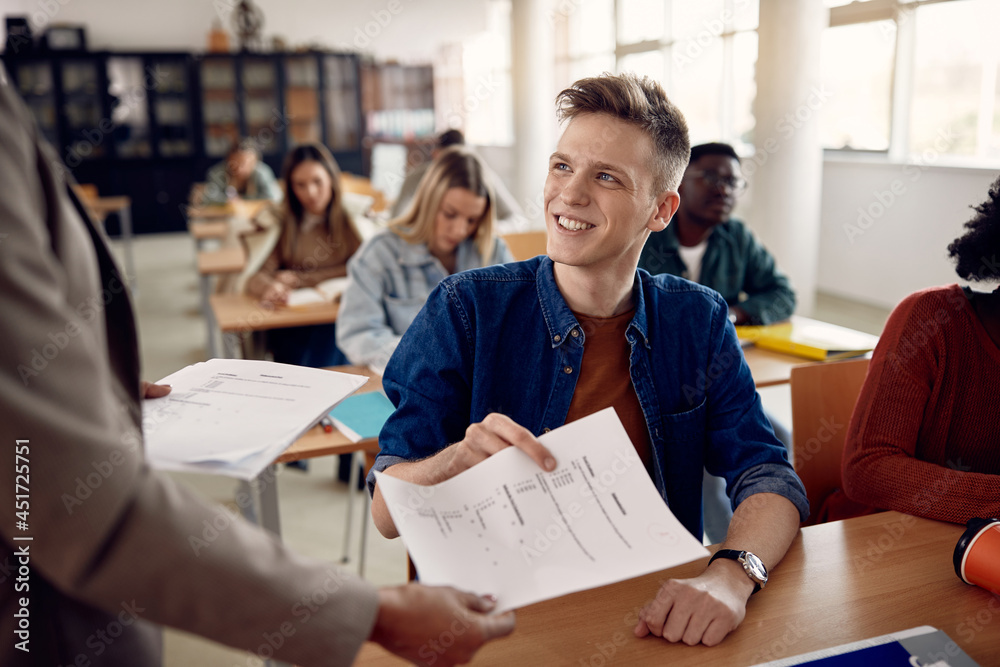 Happy college student takes exam paper from teacher in classroom. Stock ...