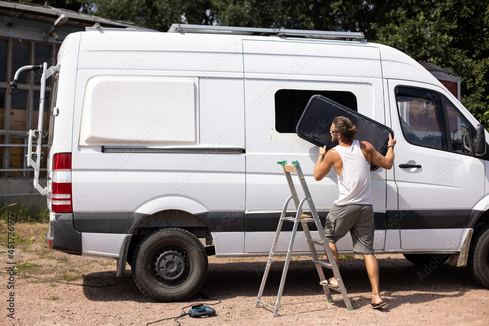 Camper van conversion - Man installing a side window Stock Photo ...