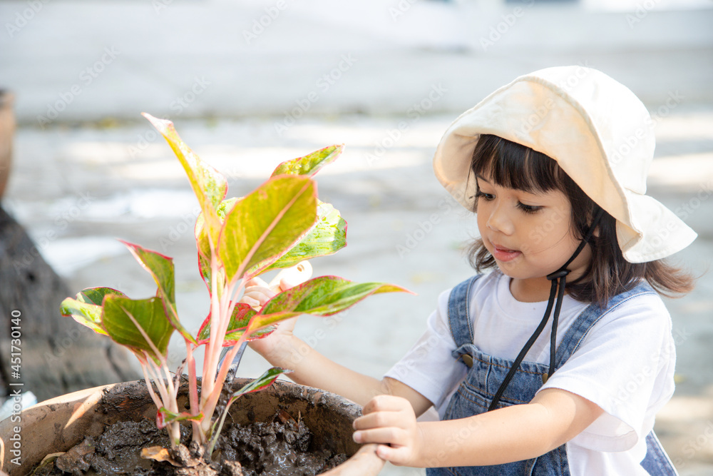 Cute Asian little girl planting the tree in the pot with happiness ...
