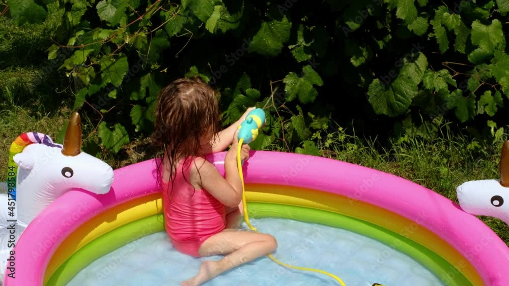 A child is swimming in the pool in the yard and shoots water from a ...