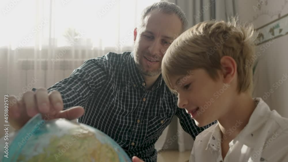 Vidéo Stock Happy dad and small kid boy talking, looking at globe ...