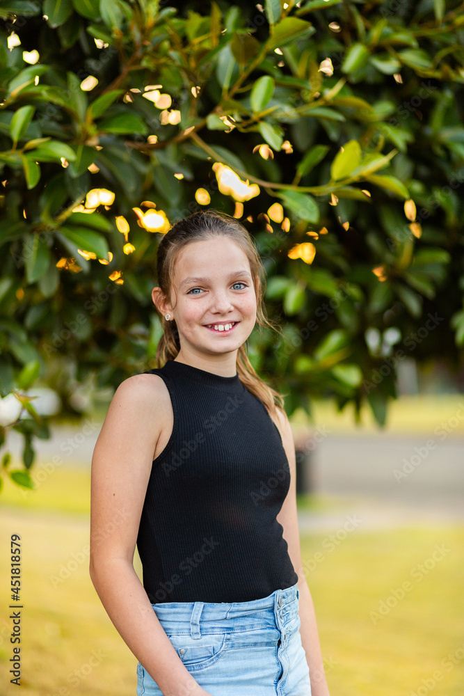 vertical portrait of smiling young tween girl against natural ...