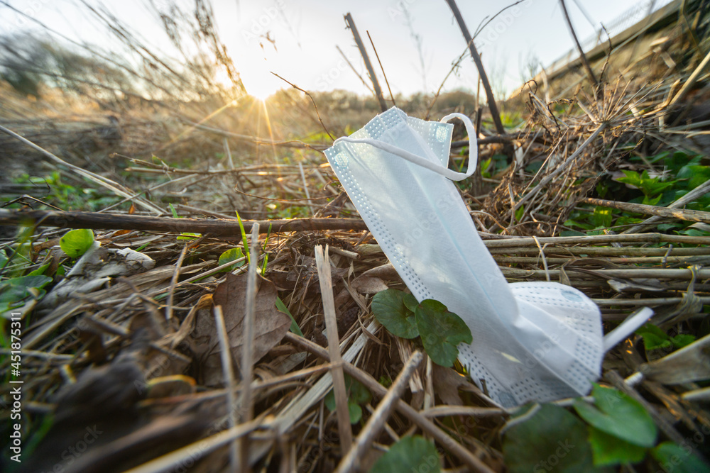 Abandoned, discarded, dumped medical pleated face mask or covering, an ...