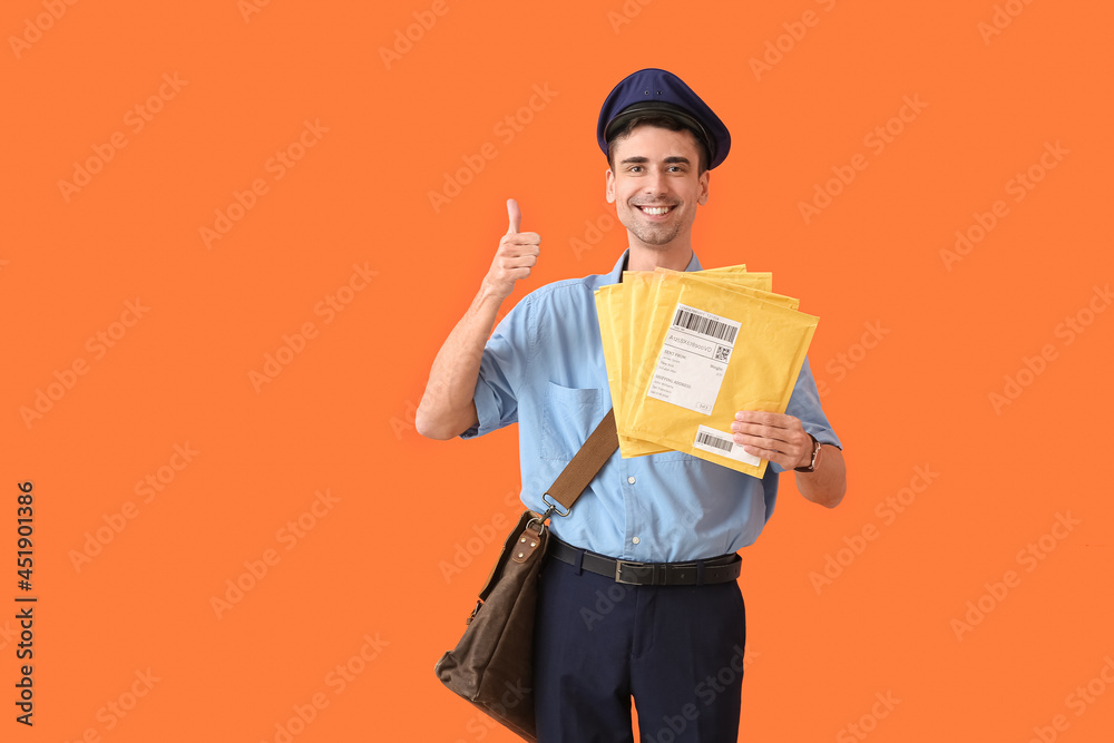 Handsome young postman with letters showing thumb-up on color ...