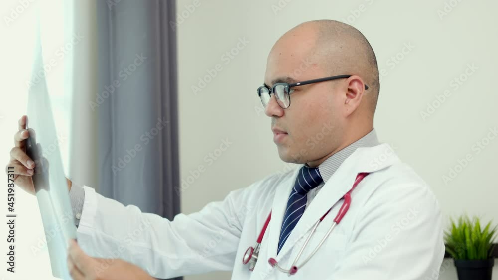 Young asian doctor working from home looking x-ray film. The patient's ...