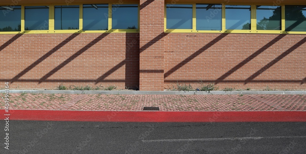 Brick wall with a row of windows. Tiled sidewalk and asphalt road in ...