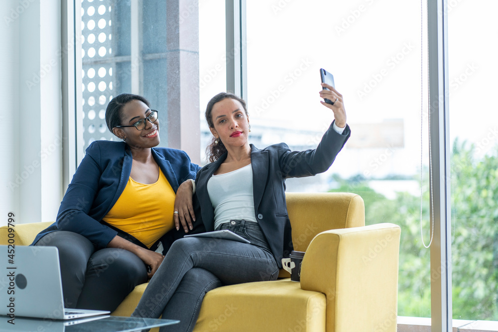 South African secretary and a Latin American roommate sit on the sofa ...