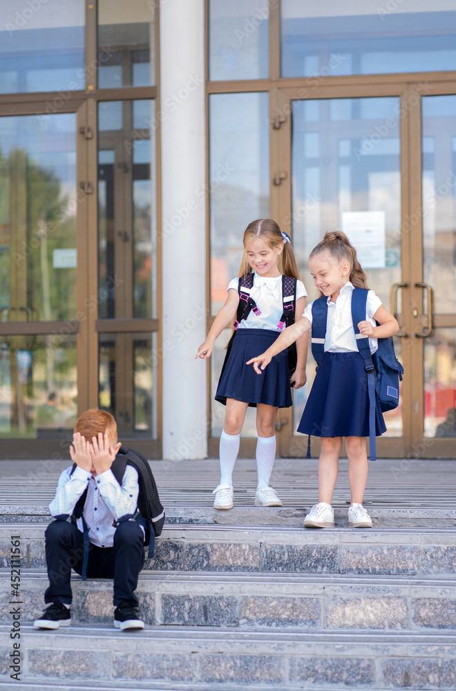 Two little schoolgirls tease a boy with red hair. A student sits on the ...