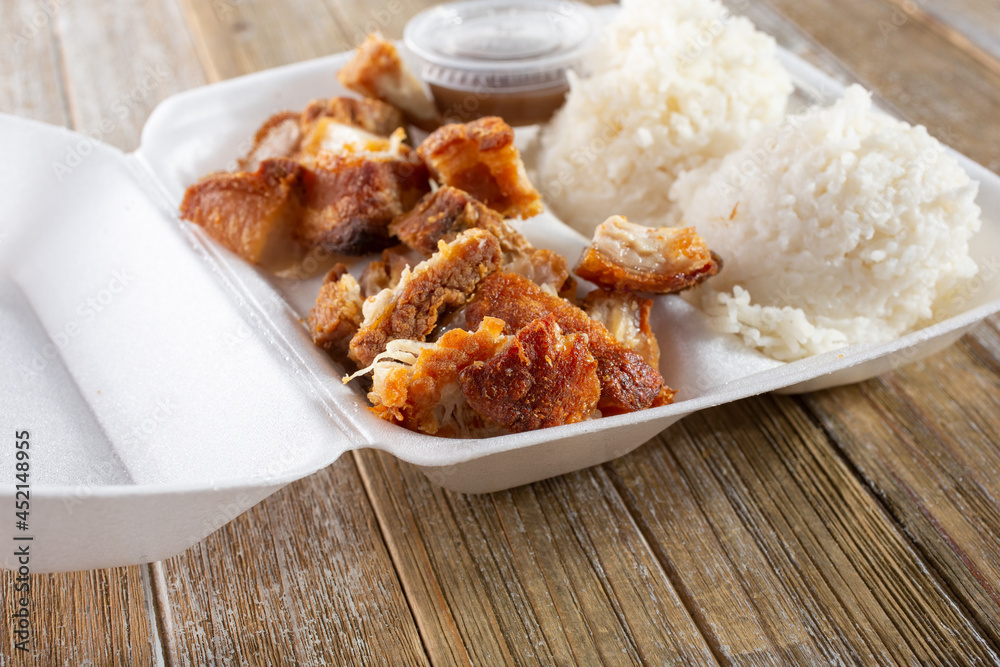 A view of a styrofoam to-go container of lechon kawali and white rice ...