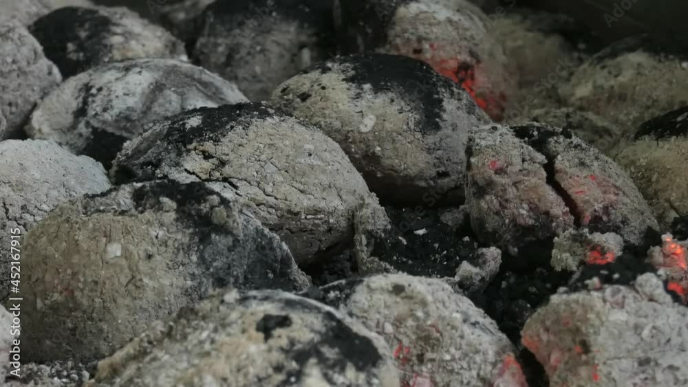 Pieces of molded coal are burning. The coals are covered with a layer ...