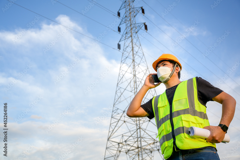 Asian male electrical engineer standing holding a blueprint at the ...