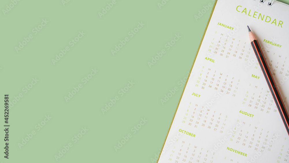 pencil on white calendar and green background, top view, for planning ...