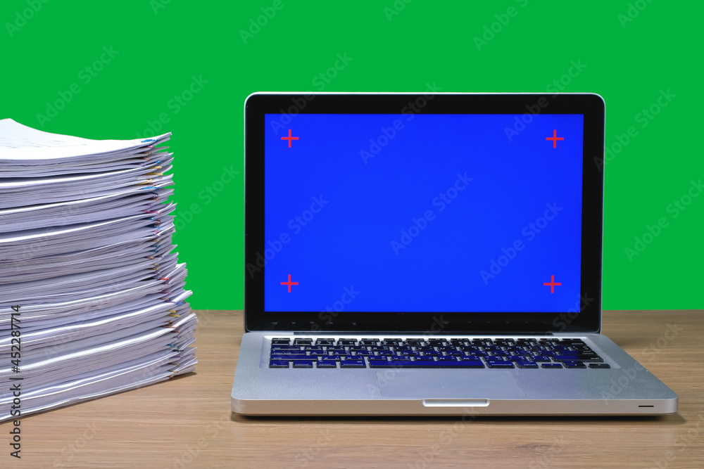 Blue screen laptop computer and Stacks overload document paper files on ...