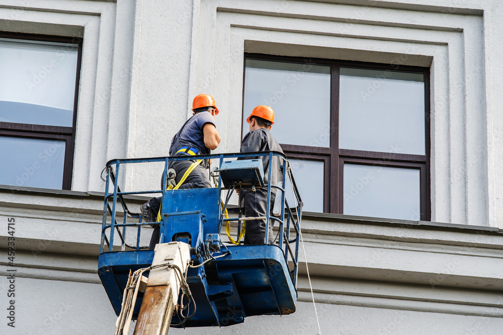 Workers are restoring the facade of the building while standing on a ...