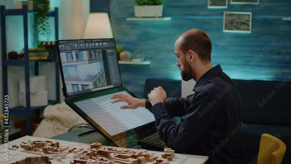 Young architect designing construction layout for building model on ...