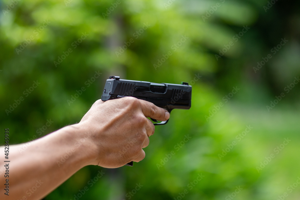 selective focus pistol in man's hand leaning forward in shooting range ...