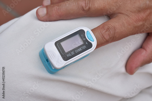 Asian Man measuring oxygen level with modern fingertip pulse oximeter ...