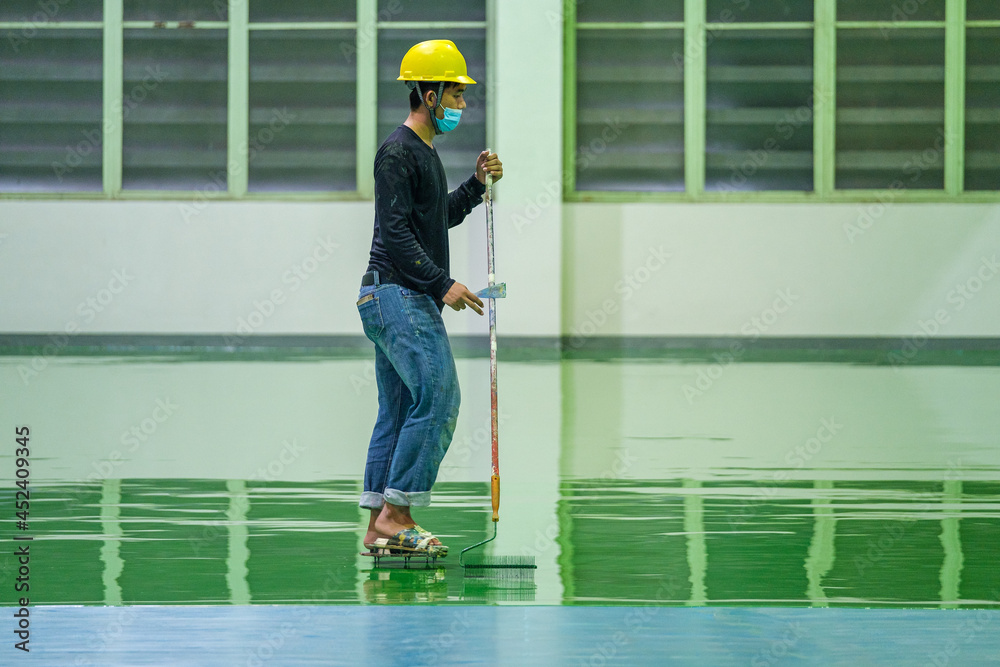 Construction workers are using rollor spreading green epoxy coating ...