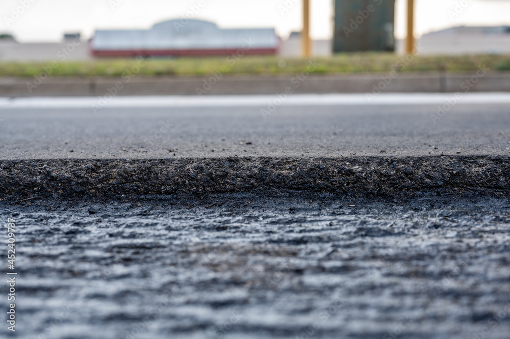 low angle selective focus on asphalt overlay paving on top of a ...