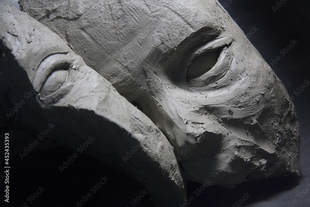 Split male face, in clay, frontal gaze on black background. Sculpture ...