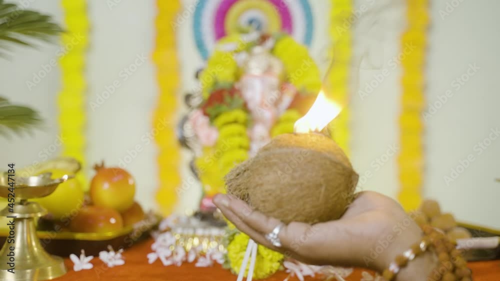 Rack focus from hands to idol, close up hands offering coconut aarti to ...