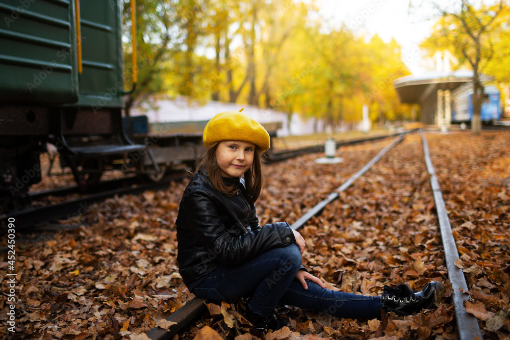 Cute little girl sitting on railway tracks. Crisp autumn day. Stock Photo | Adobe Stock