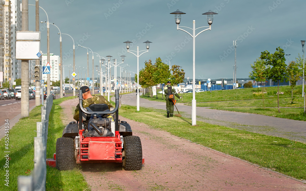 Worker ride on lawn mower. Professional lawnmower machine for cutting ...