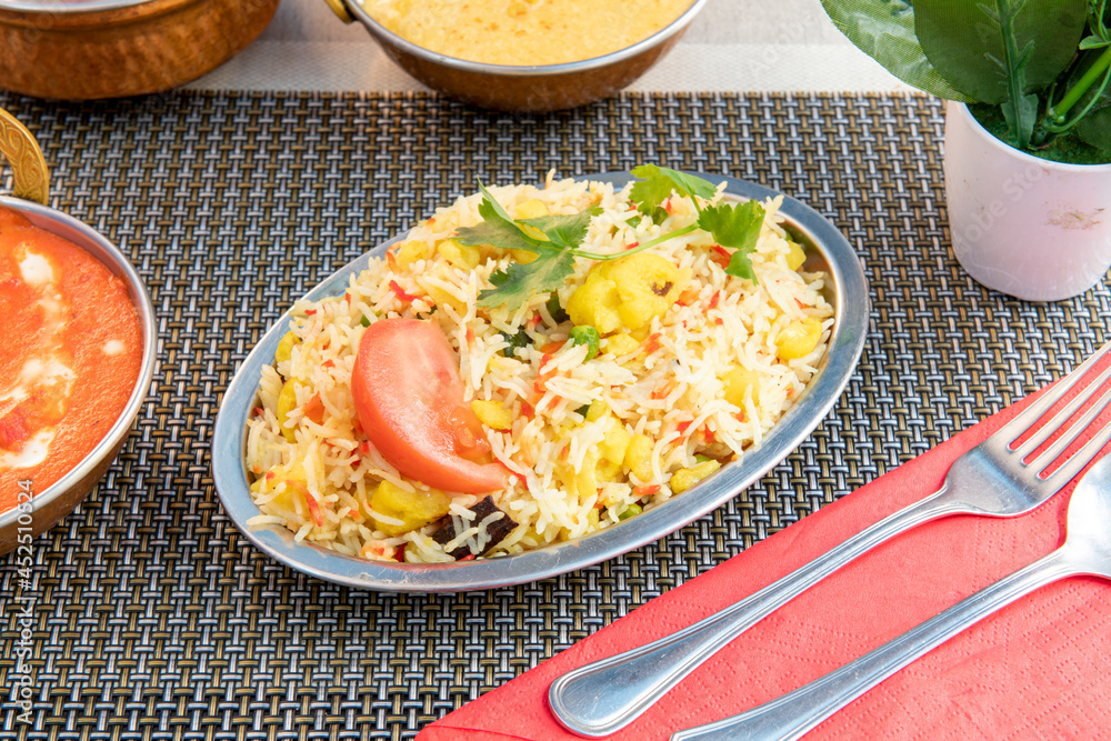 tray of biryani rice with fresh vegetables cooked in an indu restaurant ...