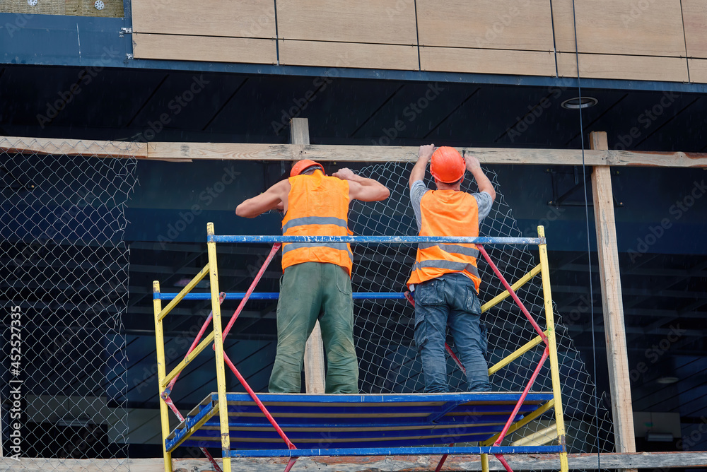 Workers team installing at height support chain-link fencing at ...