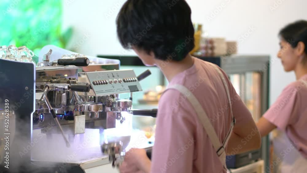Young Asian man coffee shop part time employee brew hot coffee in a ...