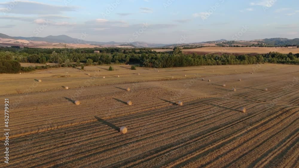 Flying over rolled hay bales on a field in Tuscany, Italy, Europe Stock ...