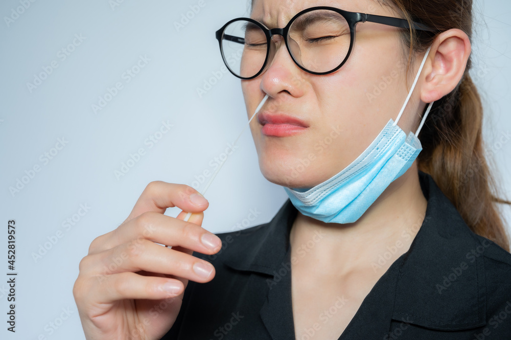Young Asian woman using rapid antigen test kit by nasal swab herself ...
