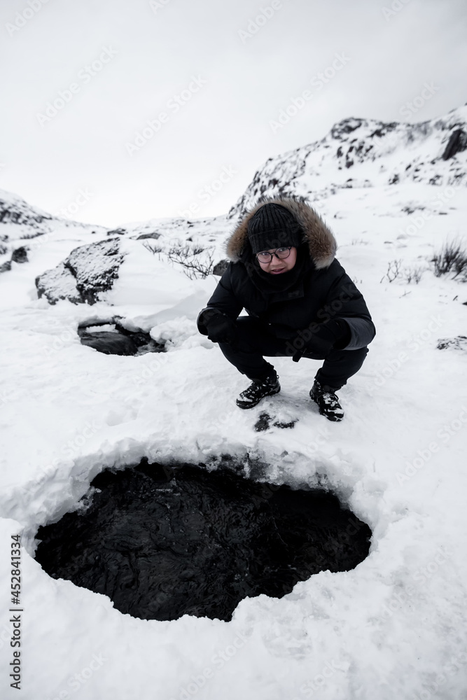 man sit front on broken ice. Crack broke the thick ice. A frozen hole ...