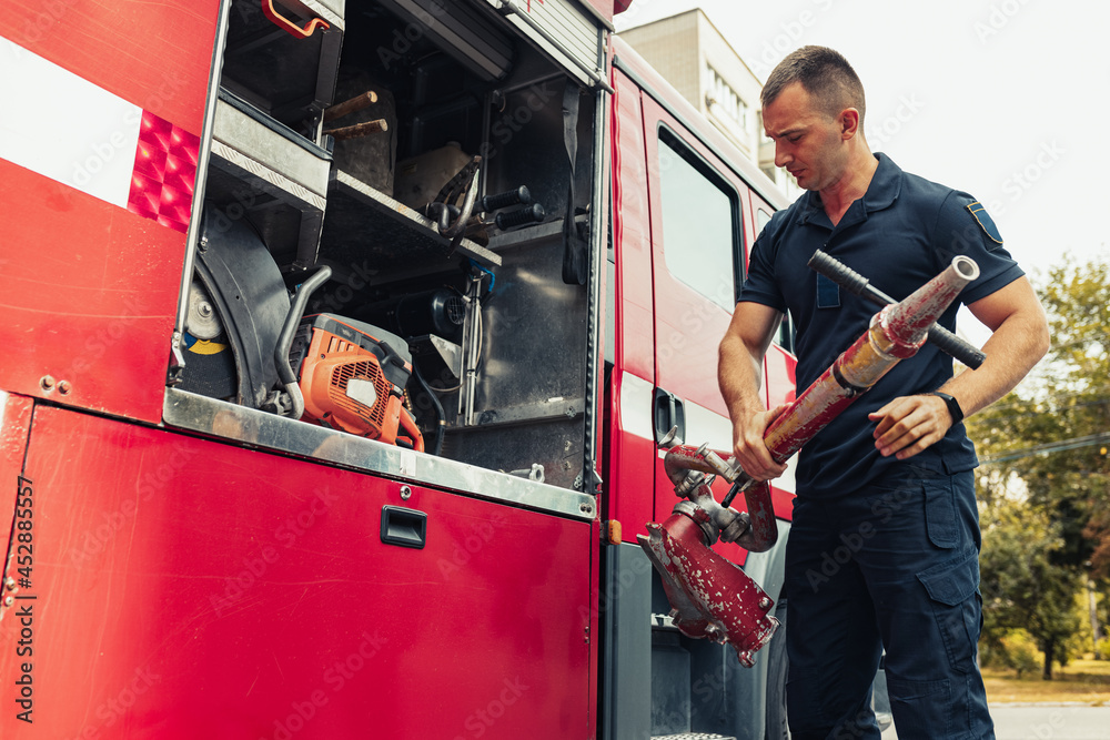 Fireman standing by fire truck, holding fire hydrant for emergency ...