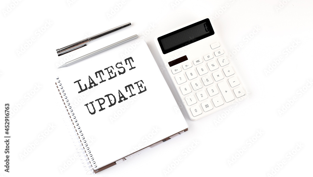 Notepad with text LATEST UPDATE with calculator and pen. White ...