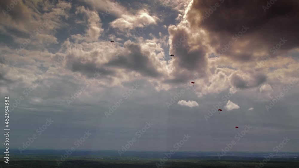 Parachutes on dramatic blue sky with sun rays passing through clouds ...