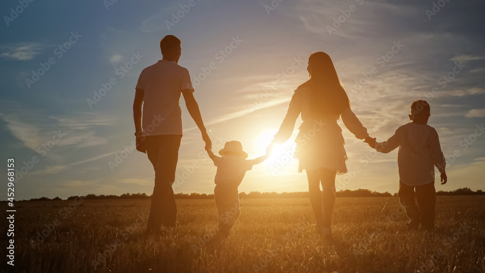 Family with children sons silhouettes walks joining hands along ...