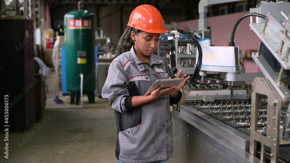 A young black manufacturing worker controls an assembly line in a ...