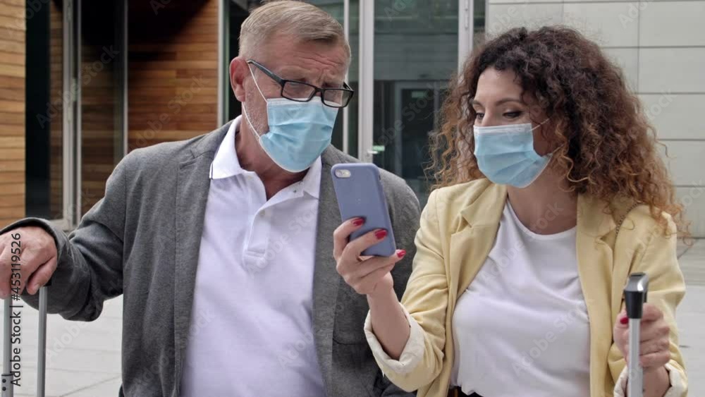 Beautiful mature couple is waiting for their flight in the waiting room. Woman showing a man ...