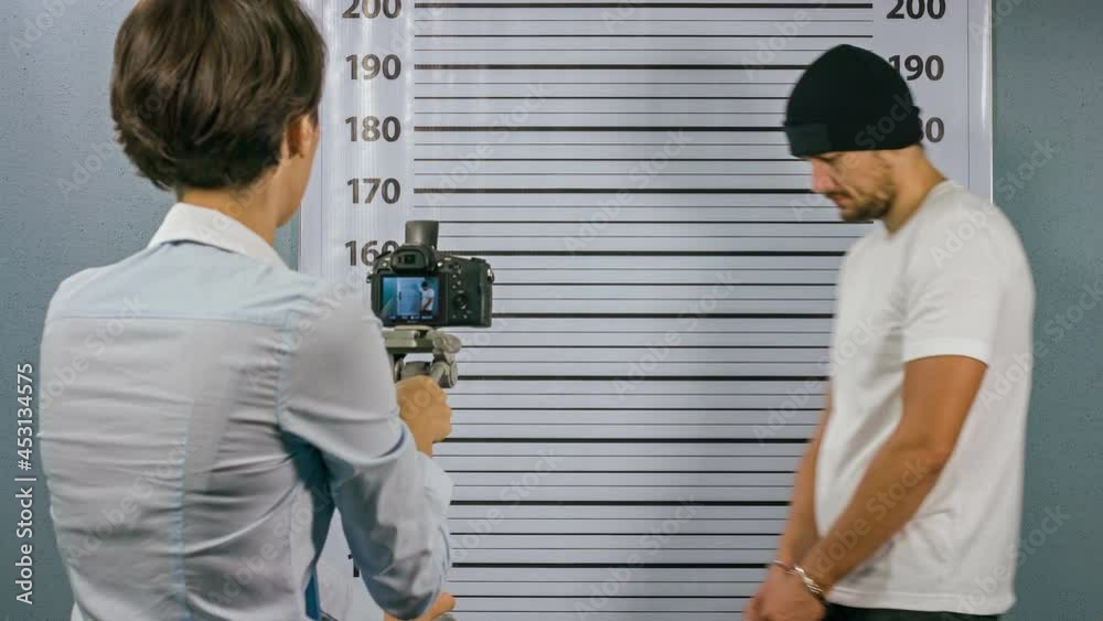 Police woman takes a picture on the camera man who is handcuffed ...