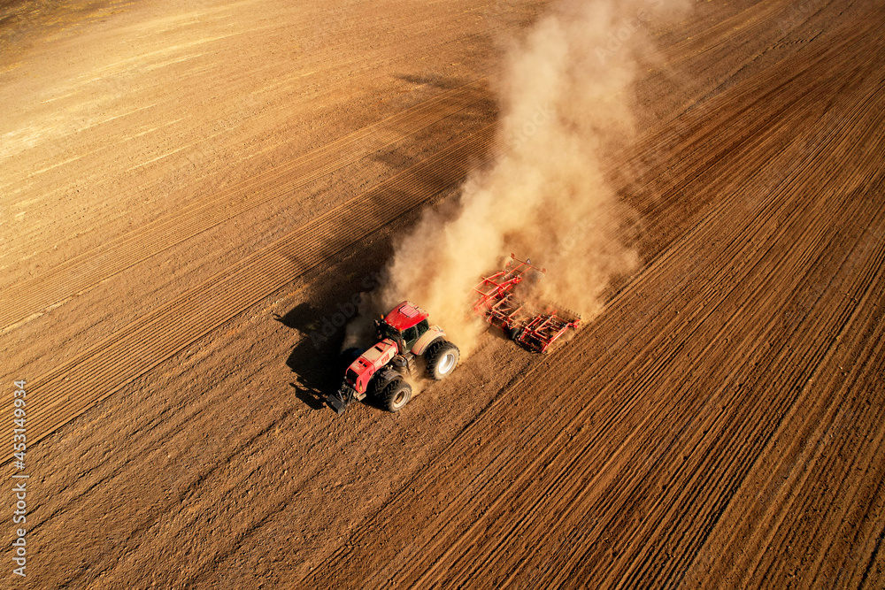 Soil Tillage in farmers country. Red Tractor on cultivating field work ...