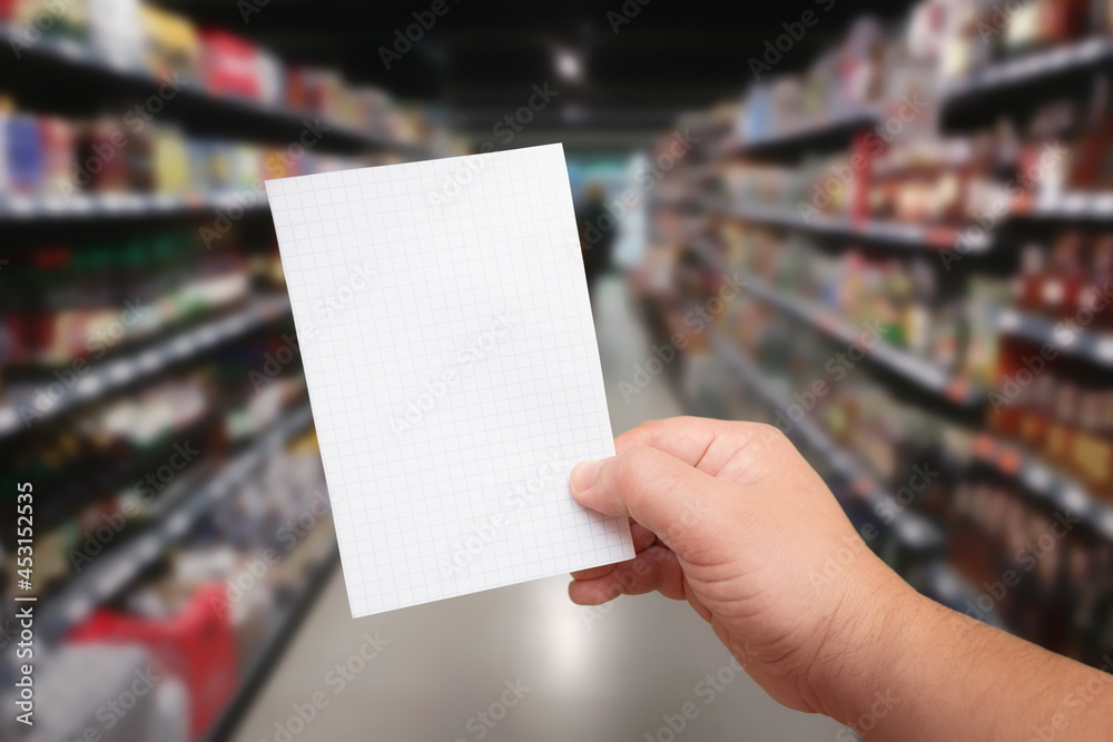 Paper for shopping list in hand at blurred background with supermarket ...