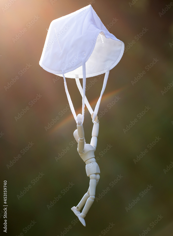 Wooden figure flying with respirator mask as parachute, destined to ...