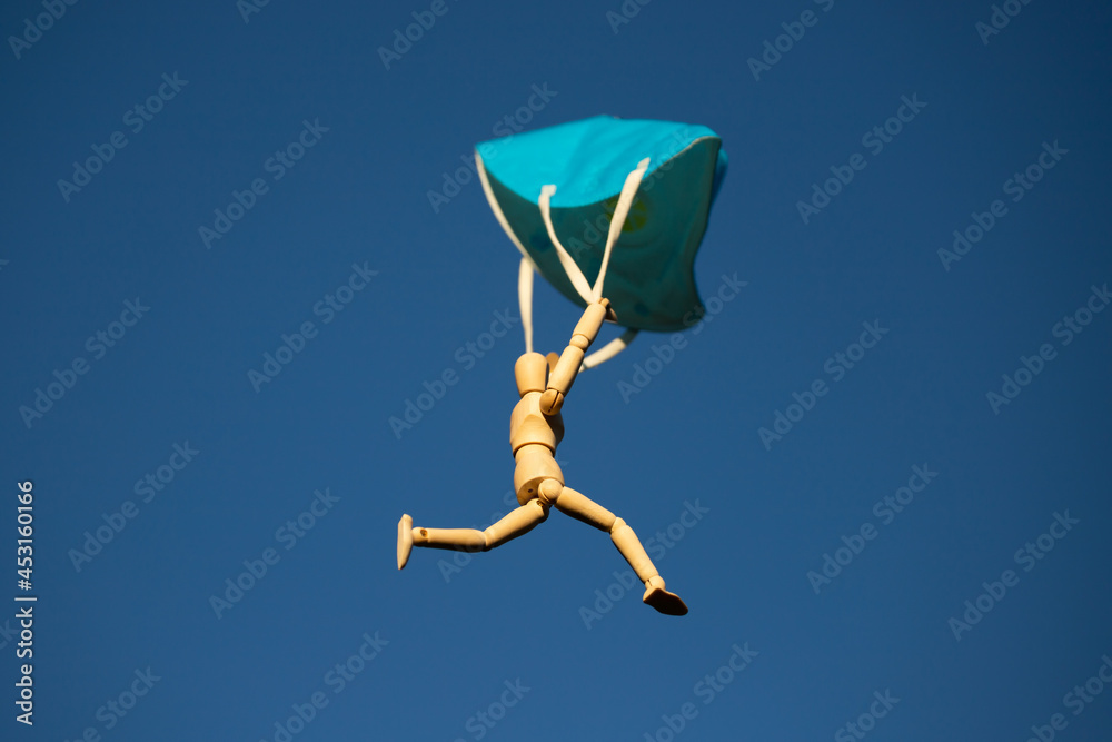Wooden figure flying with respirator mask as parachute, destined to ...