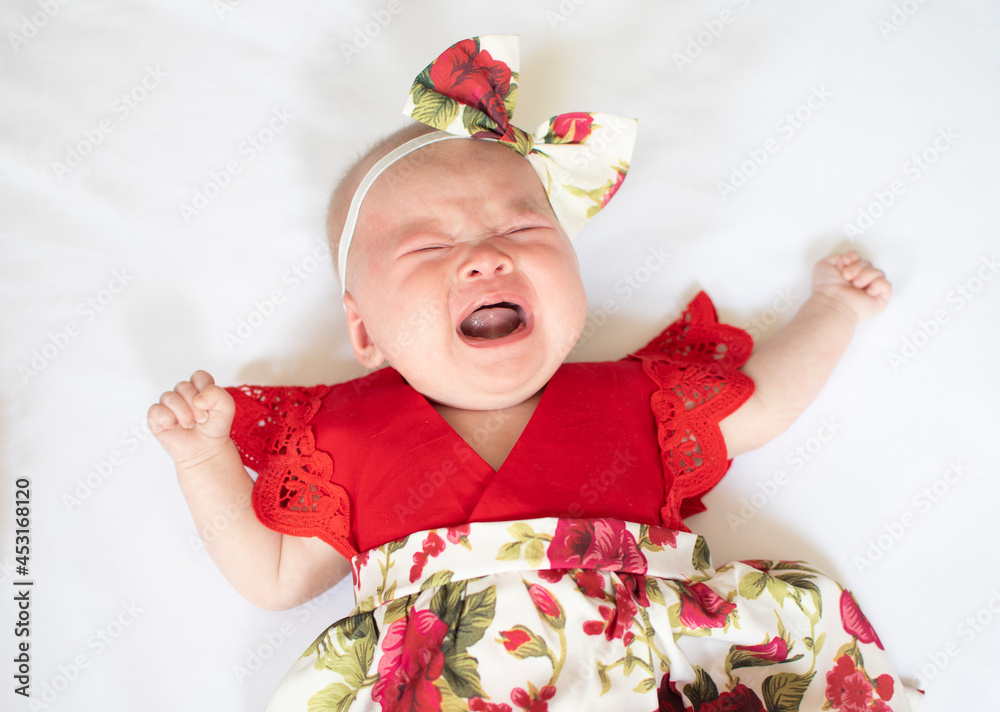 crying caucasian baby girl in a red dress. Crying child. Stock Photo ...