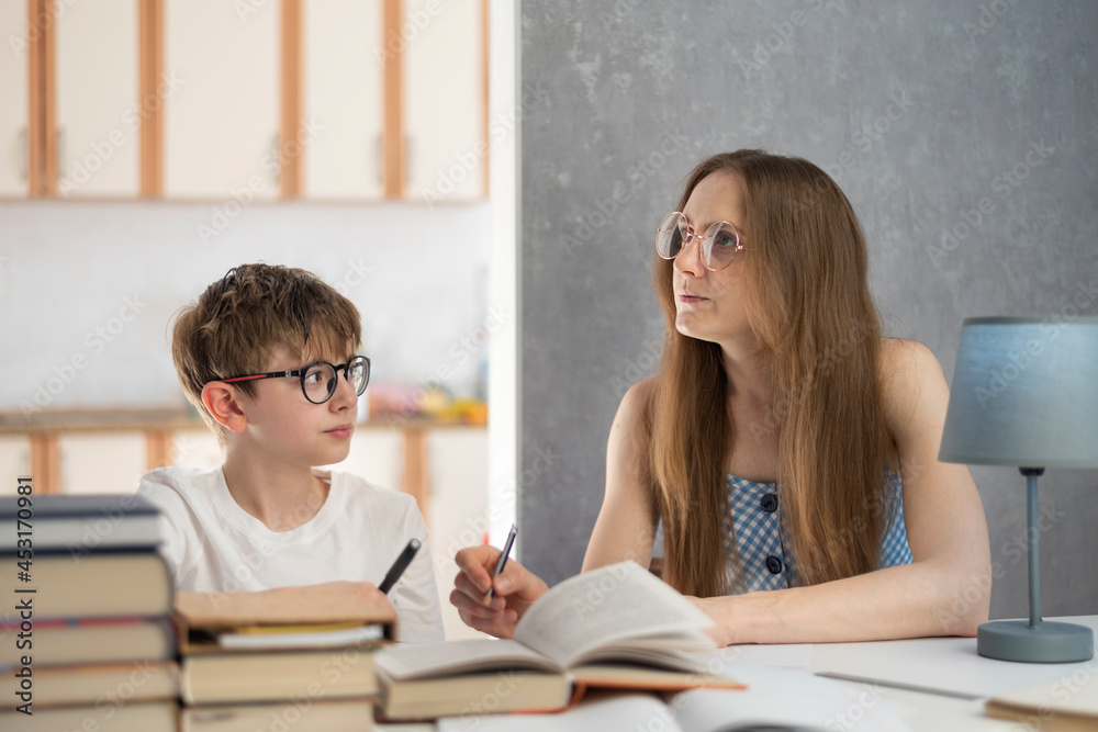 Foto de Boy in glasses and young teacher are doing homework together ...