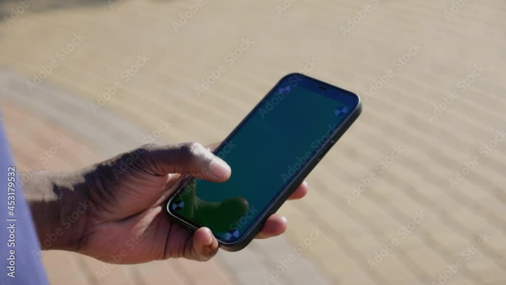 Afro-american man holds smartphone in hand, finger touches smartphone ...