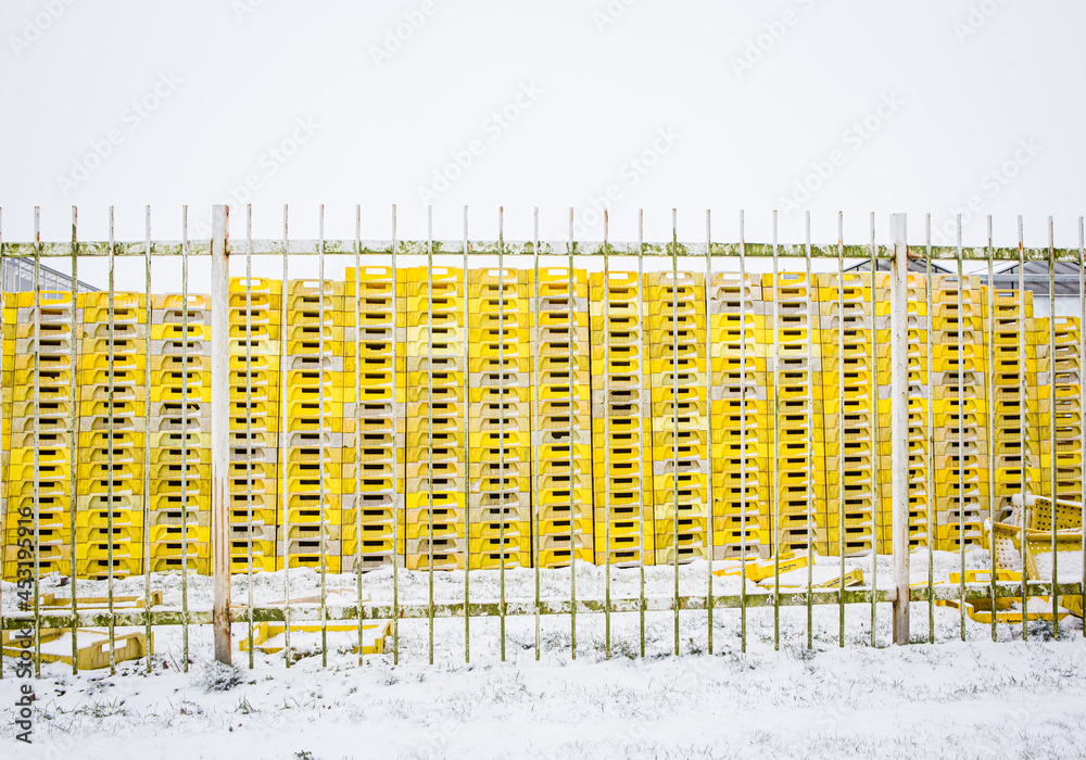 Yellow pallets piled on top of each other behind a fence. Stock Photo ...
